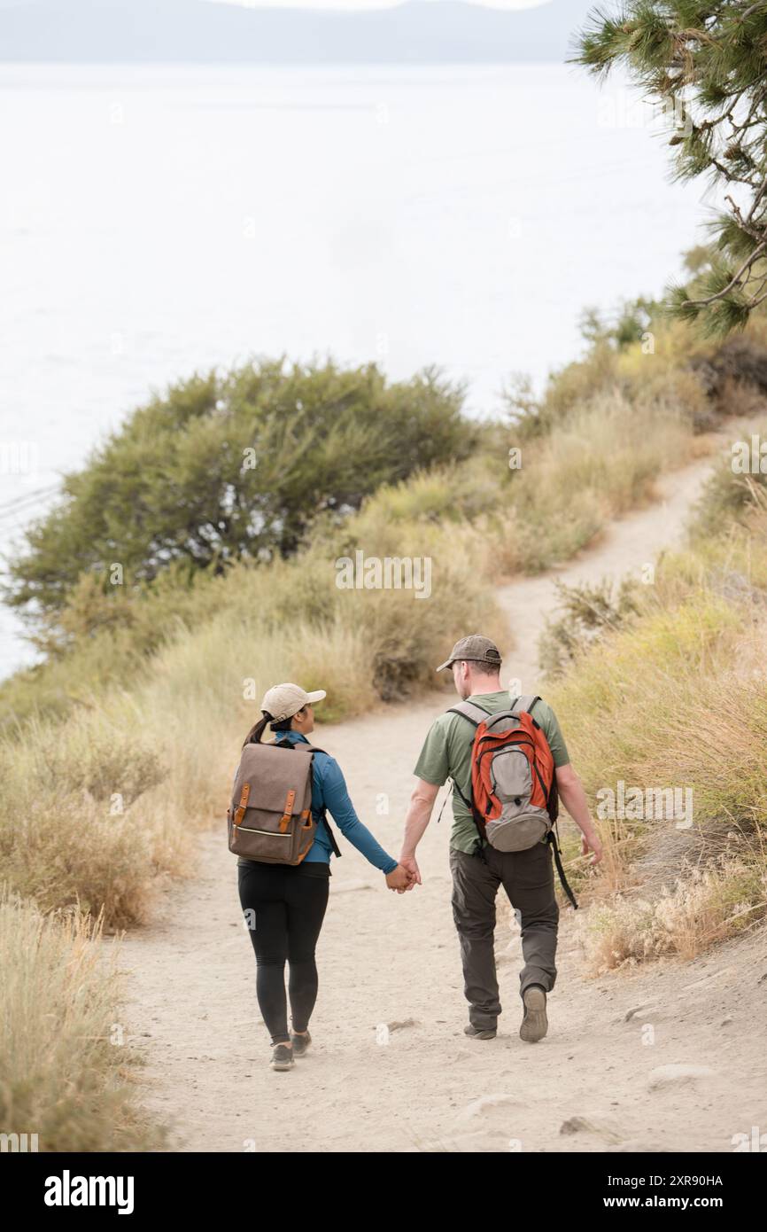 Couple hikers holding hands walking on a trail Stock Photo - Alamy