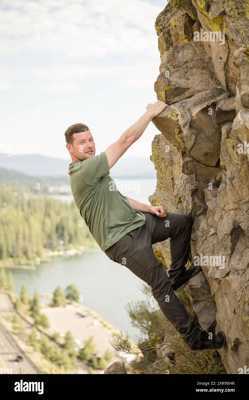 Male hiker climbing up a cliff looking at the camera Stock Photo - Alamy