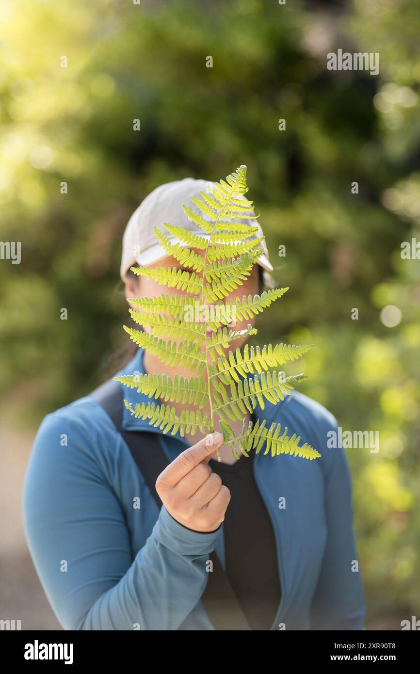 Woman holding a fern leaf in front of her face Stock Photo - Alamy