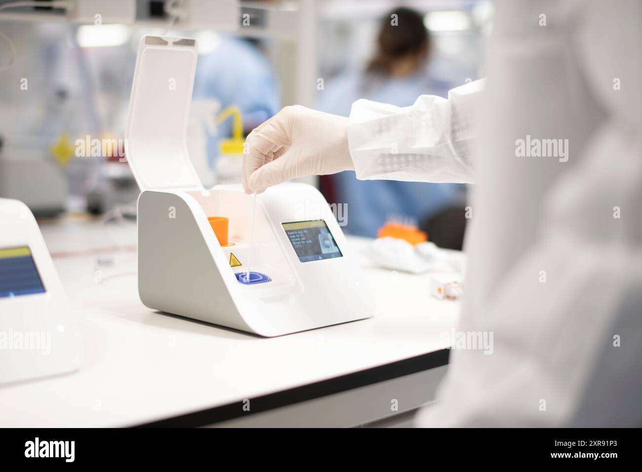 Lab technician placing swab into point-of-care testing machine f Stock ...