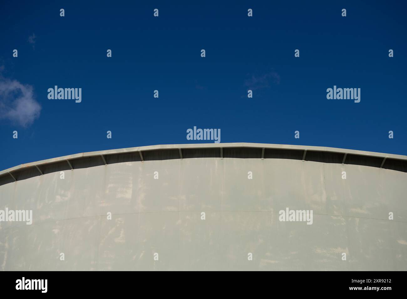 Pale green large scale water storage tank against a deep blue sk Stock ...