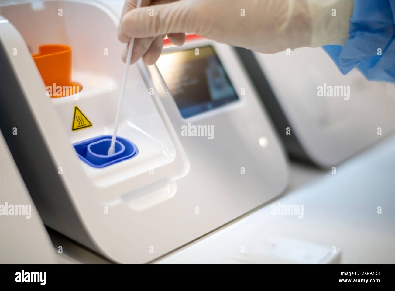 Lab technician placing swab into point-of-care testing machine f Stock ...