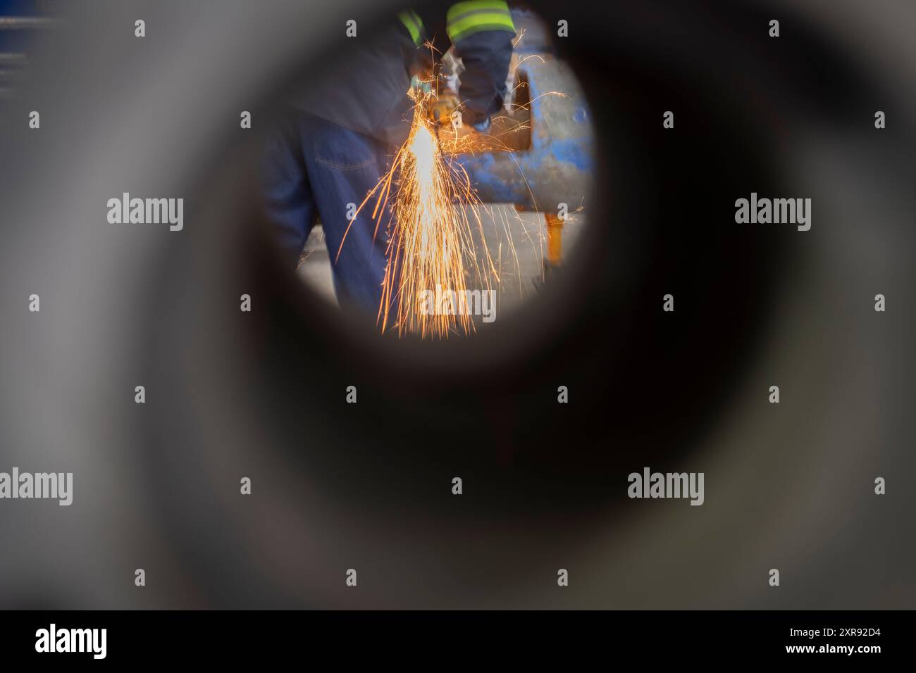 Sparks flying from worker grinder seen through a round pipe Stock Photo ...