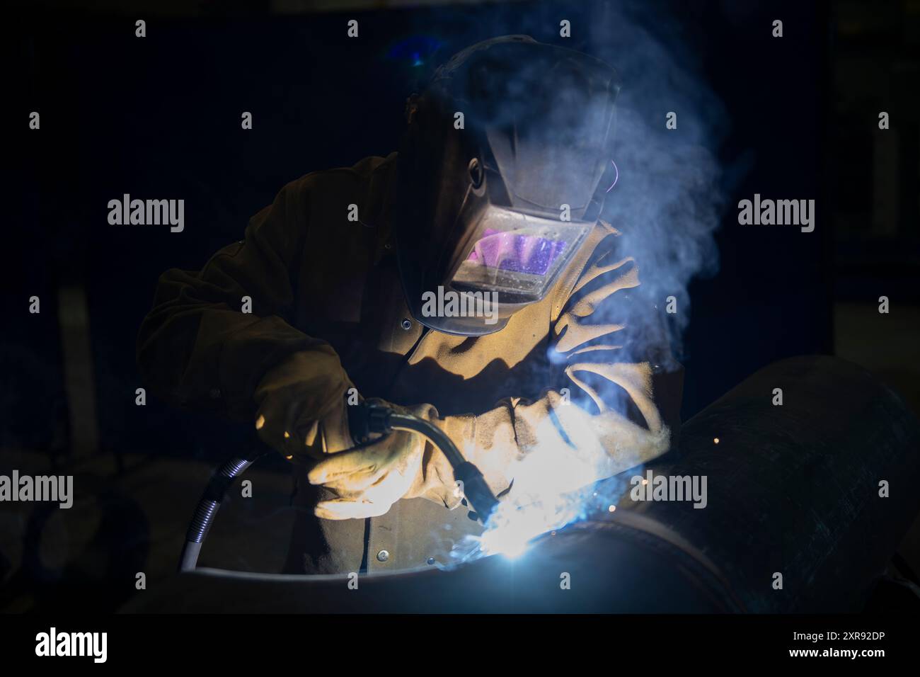Welder welding a pipe working in a dark environment Stock Photo - Alamy