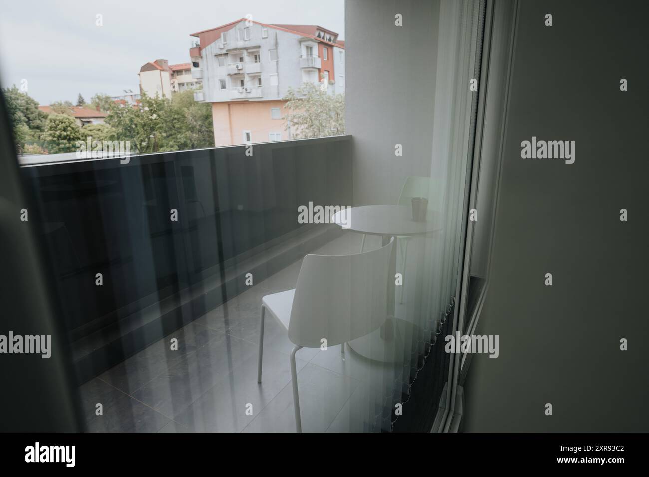 Modern apartment balcony with small table and chair overlooking urban ...