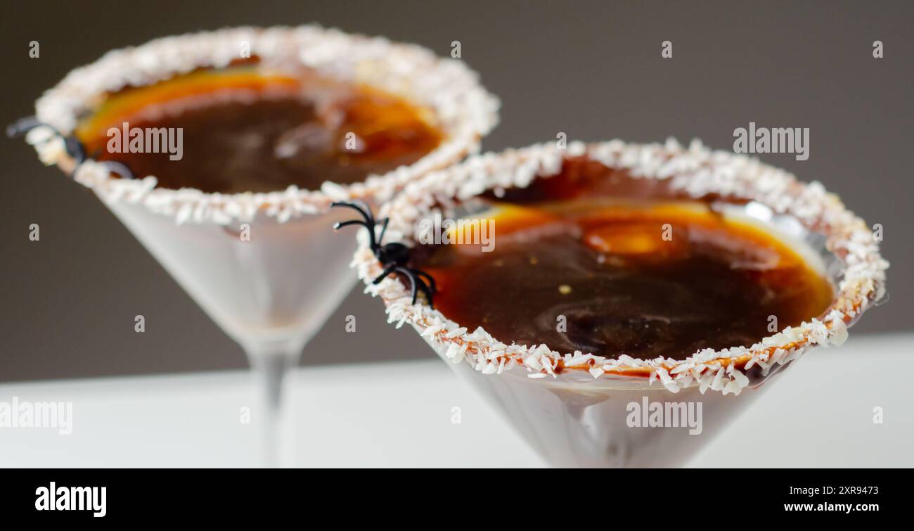 Two martinis with black spider decorations on top. The martinis are in ...