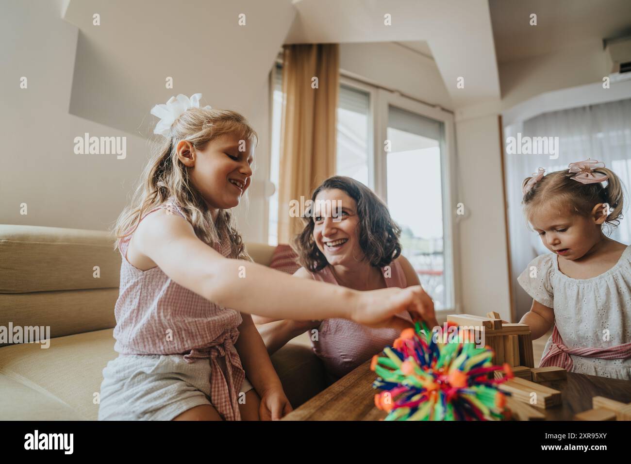 Mother spending quality time with daughters playing indoors and having ...