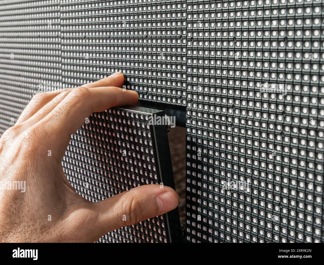 Close-up of a man's hand installing a square LED module into its place ...