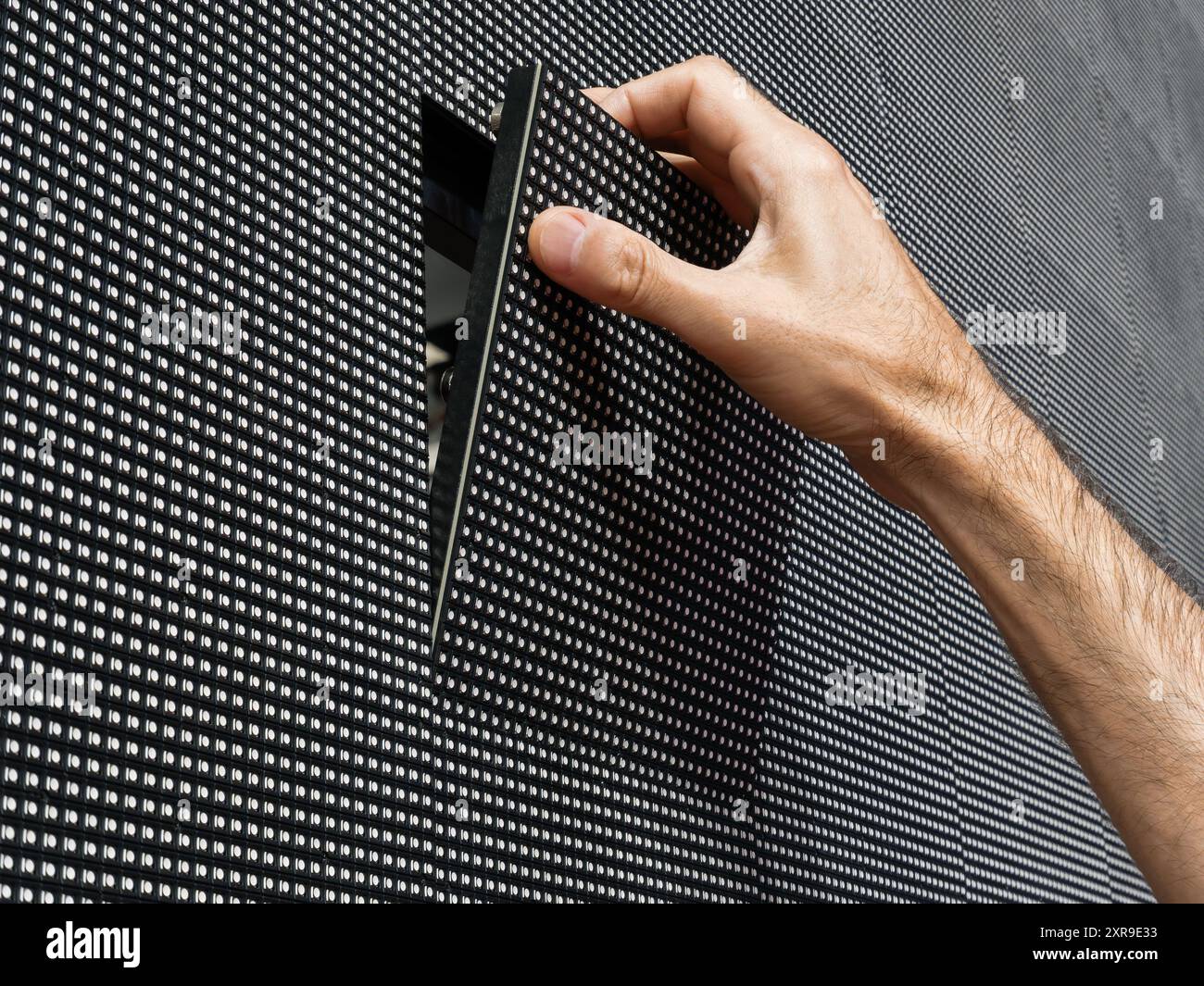 A man's hand removing a square LED module from its place on the surface ...