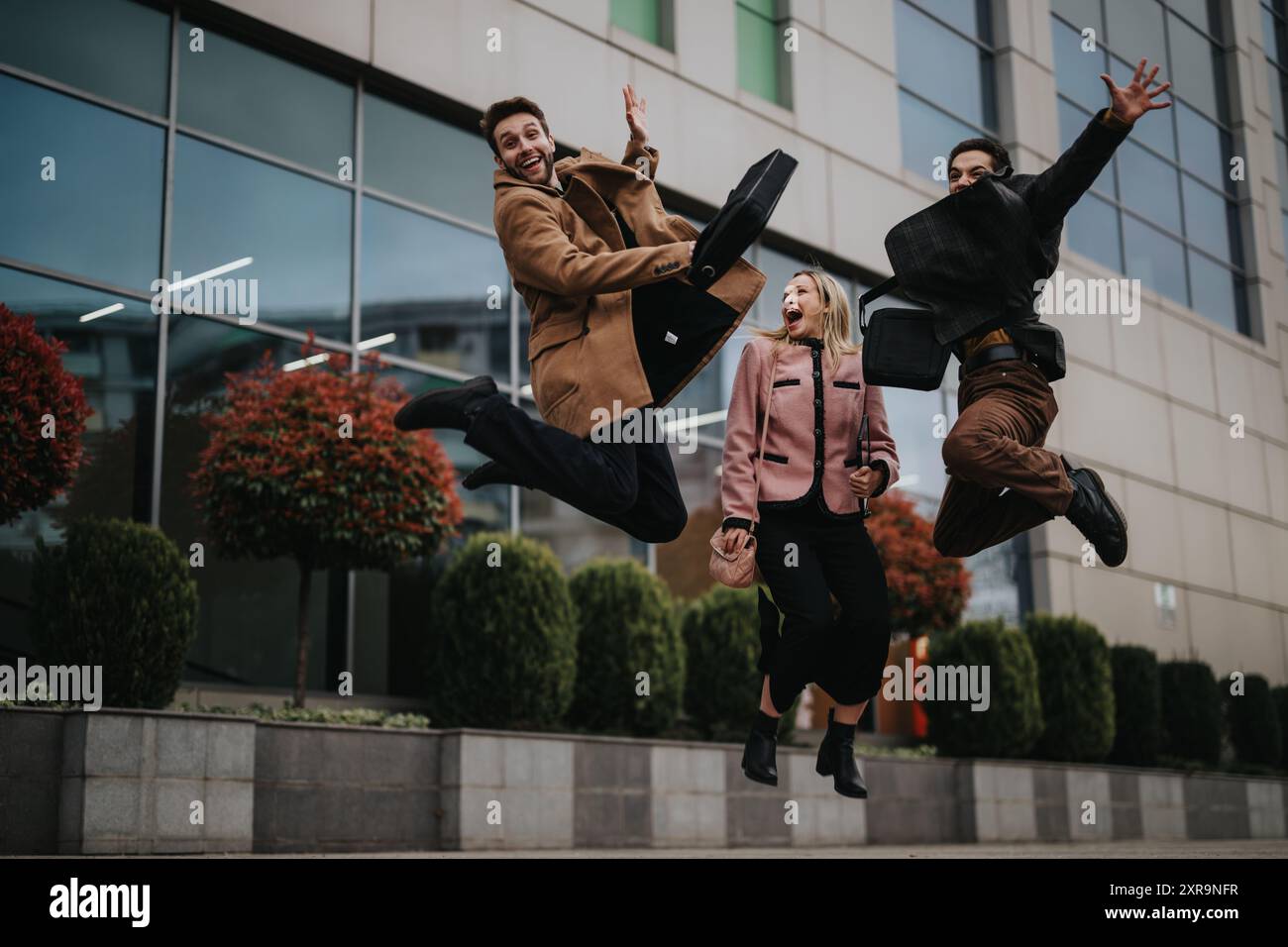Energetic young business people jumping with joy outside a modern ...
