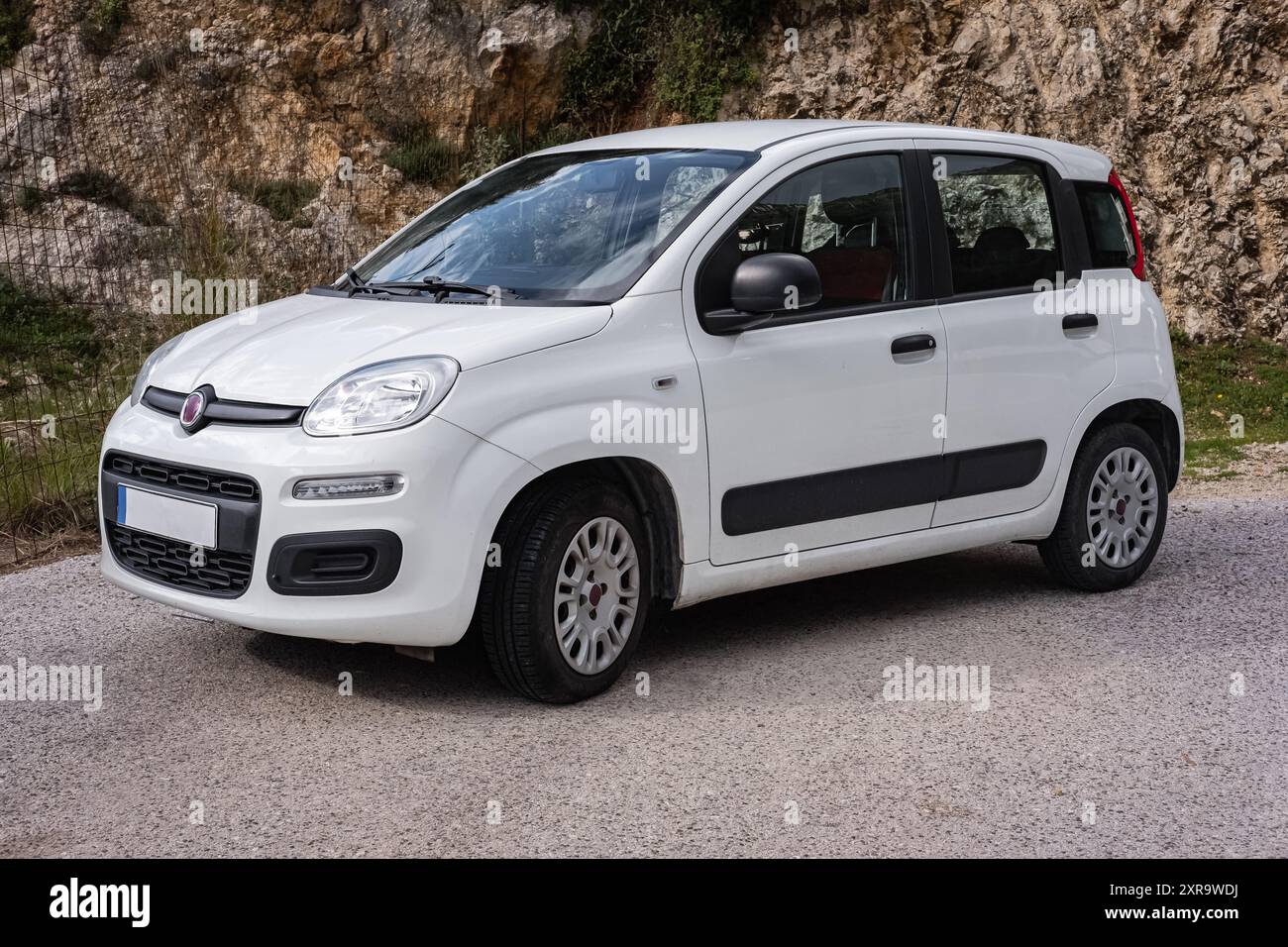 Small mini car parked on the side of a road. White hatchback cars on ...