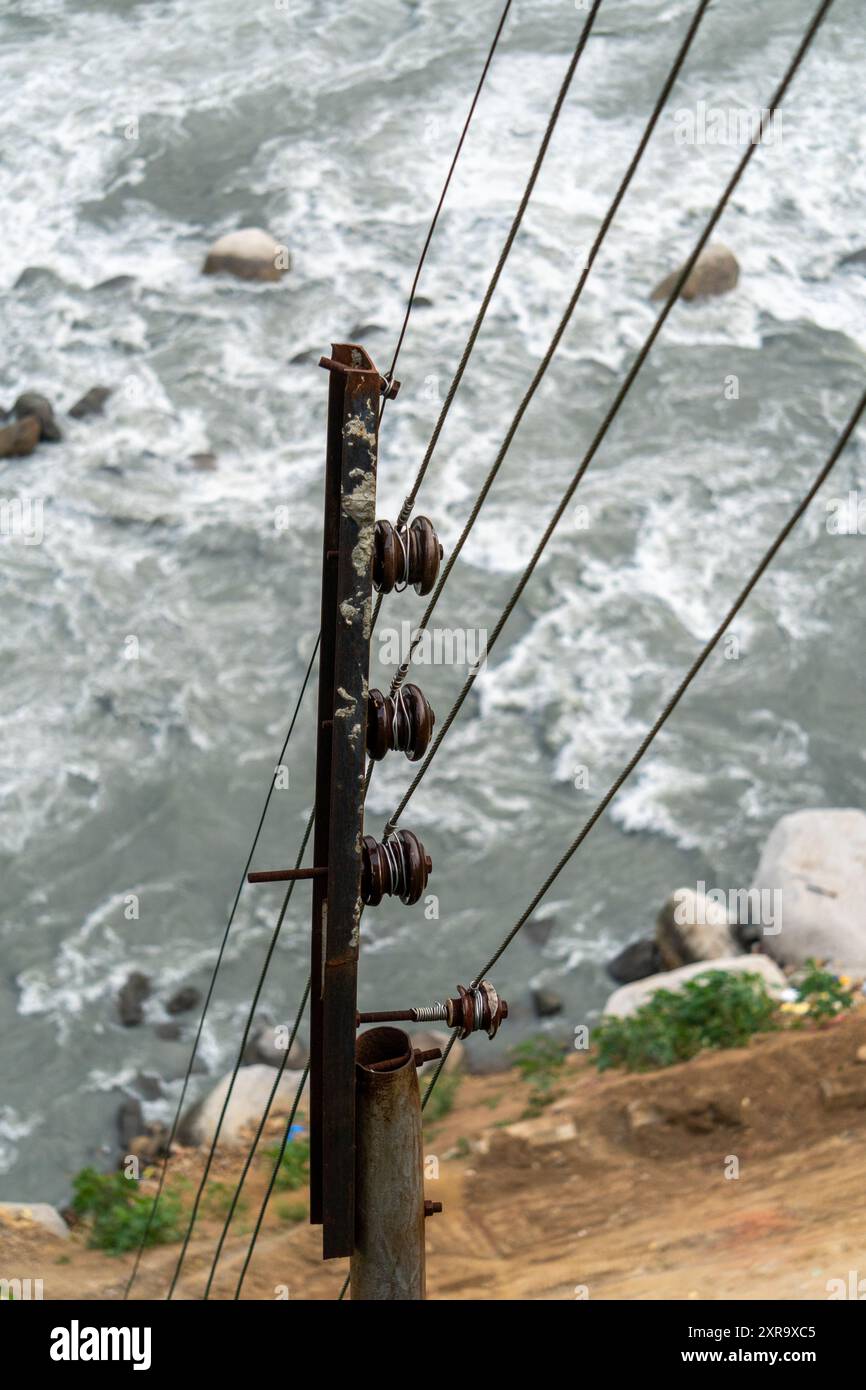 A riverside electrical pole equipped with high voltage wires and ...