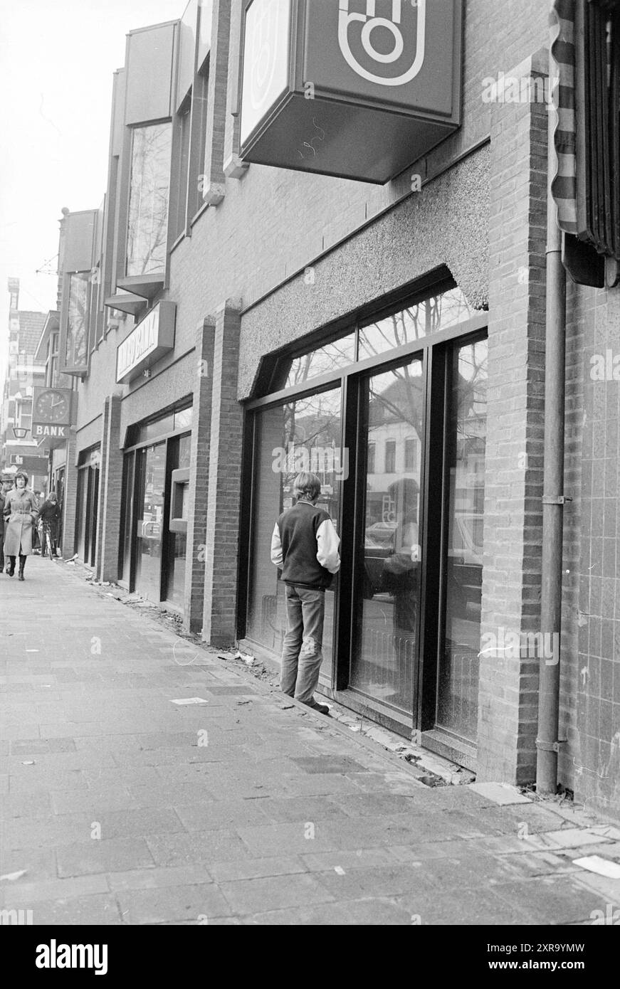 Man in front of the Amro Bank facade in a shopping street, 24-12-1979 ...