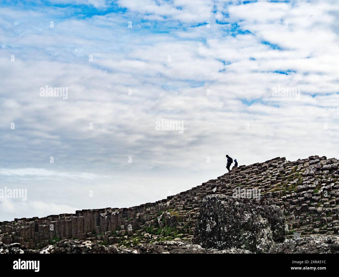 A couple climbing the hexagonal stones. The Giant’s Causeway and ...