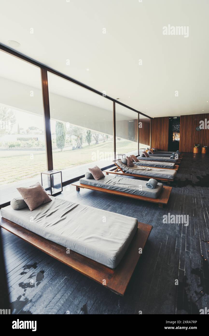 A serene indoor swimming pool lounge area with modern wooden loungers ...