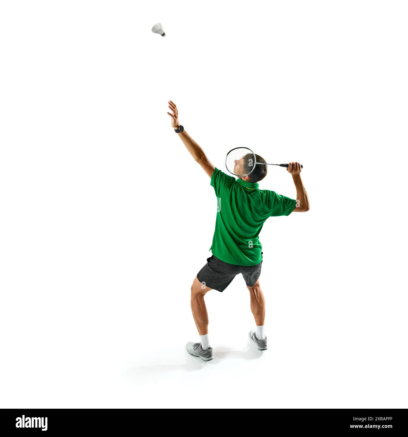 Full-length image of young men, badminton player serving shuttlecock ...