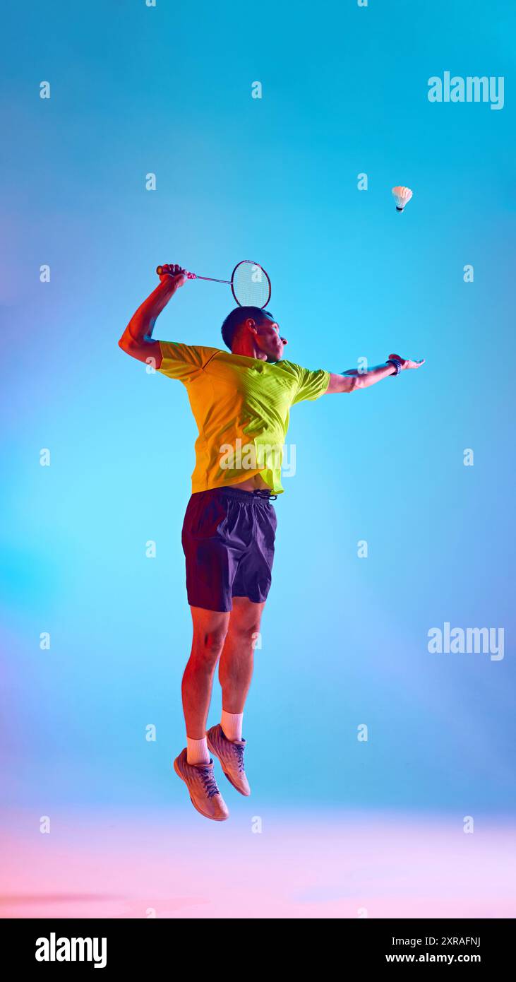 Full-length image of young concentrated badminton player, man hitting ...