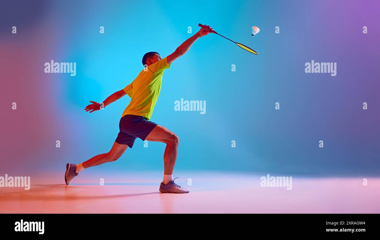 Young man in black and yellow sportswear in motion with racket, playing ...