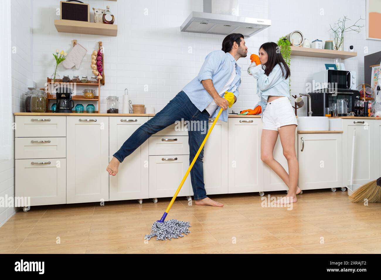 Young happy couple having fun while doing cleaning kitchen. Happy ...