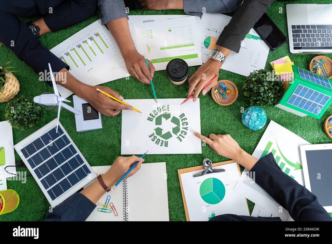 Group of businessmen's hands touching green recycling symbol, showing a ...