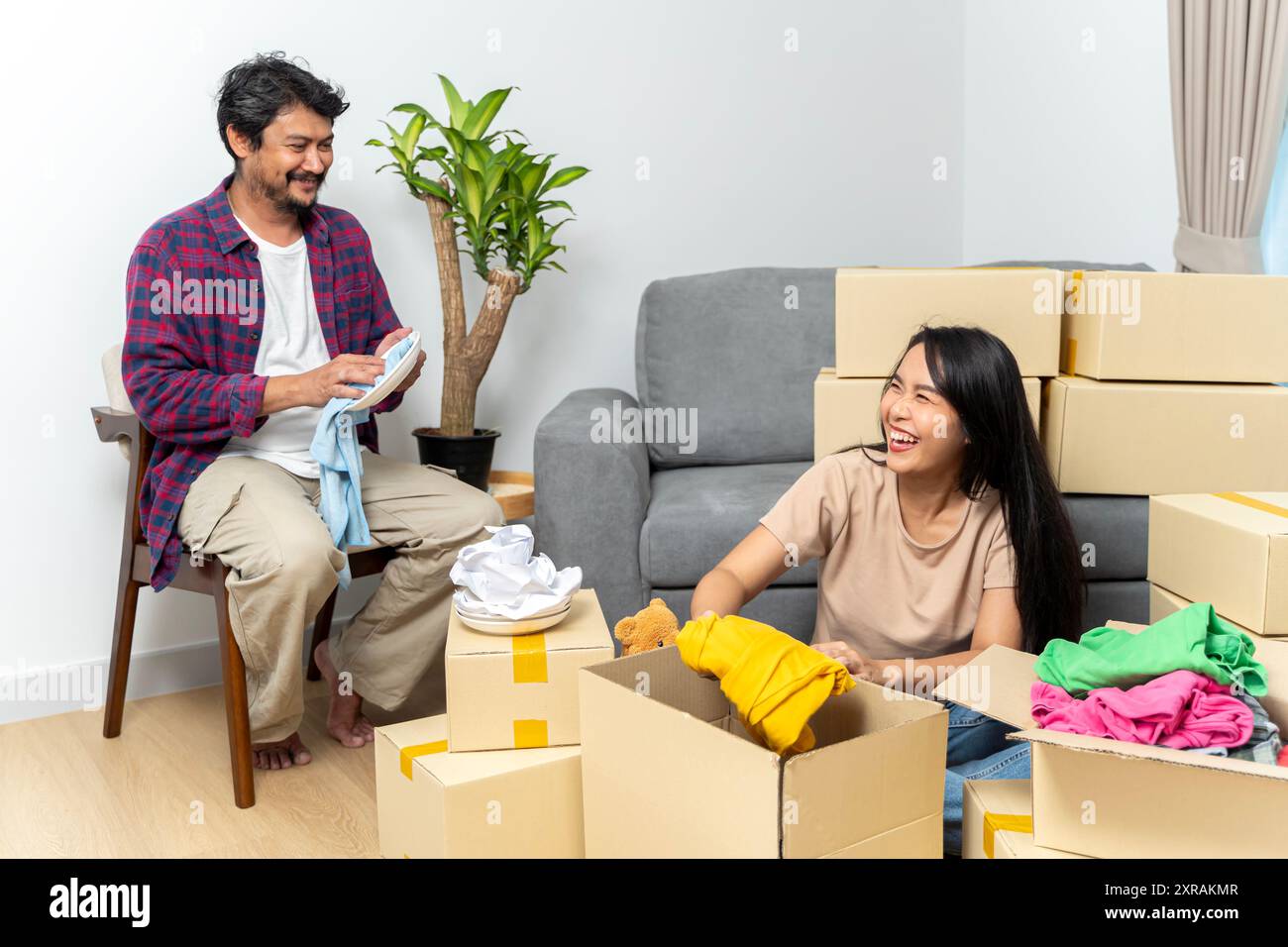 Couple recycle, donate and packing boxes for relocation while moving house for sustainability ...