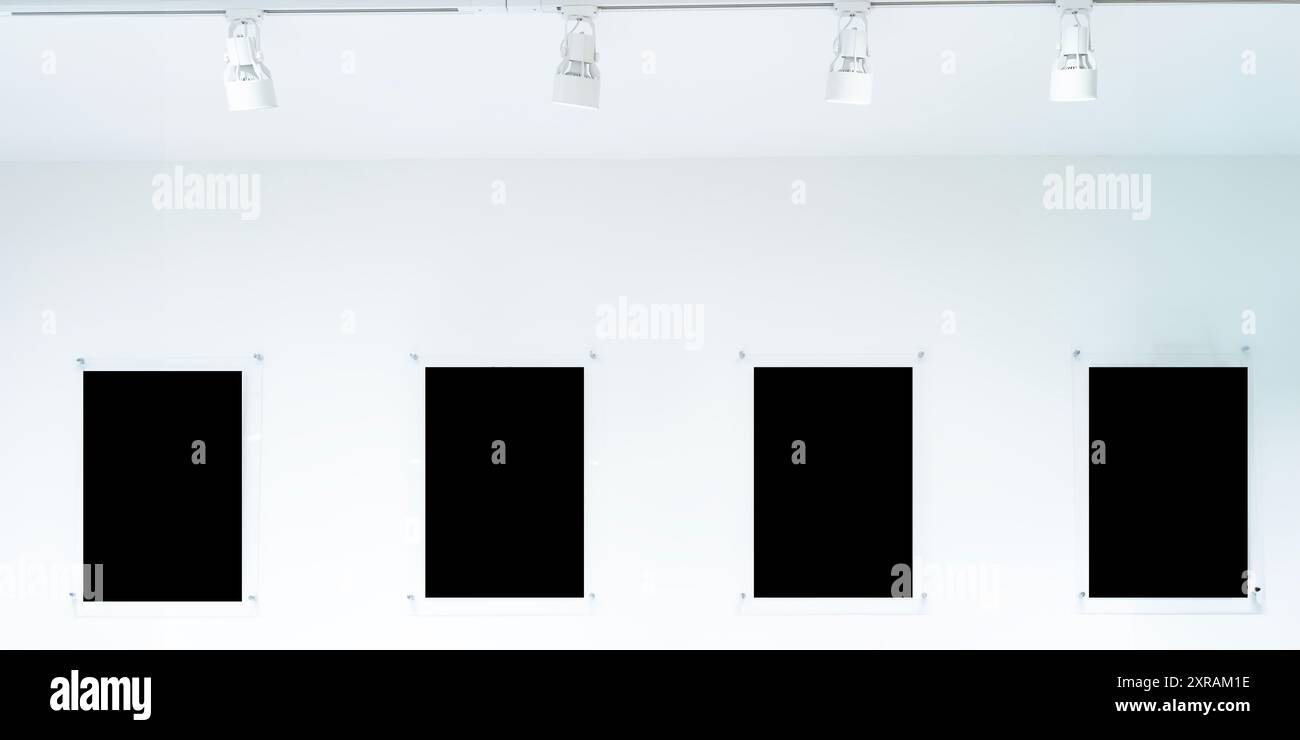 A row of black frames hang from a white wall. The frames are all ...