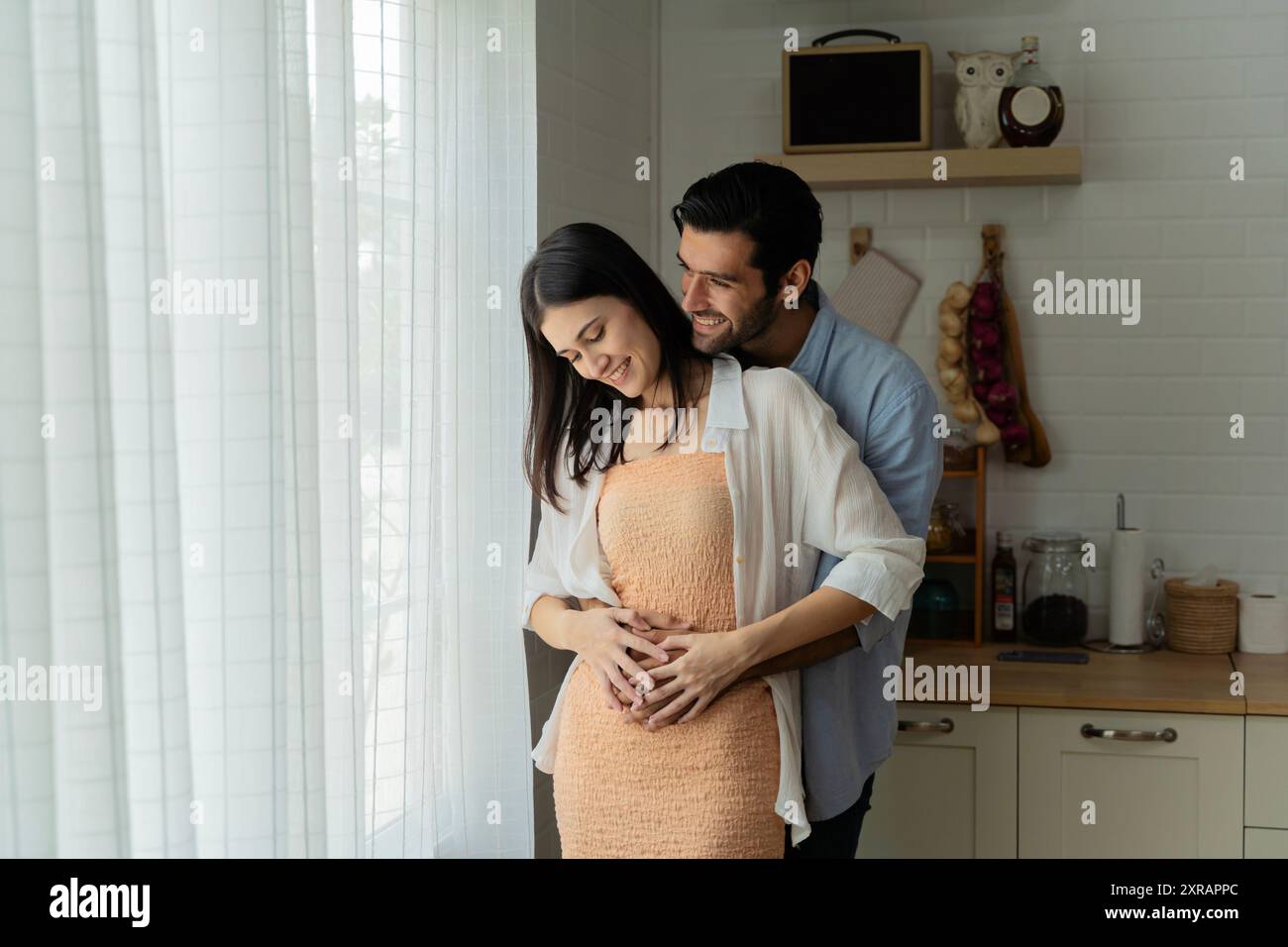 Pregnant woman and her husband holding hand in heart shape on baby bump ...