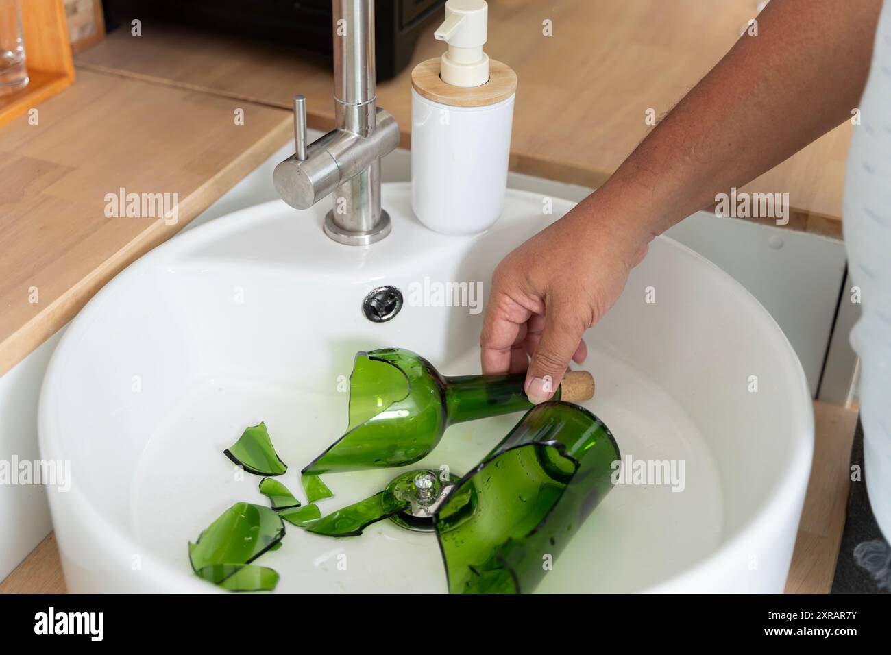 Broken green glass bottle inside white sink in modern kitchen.Broken ...