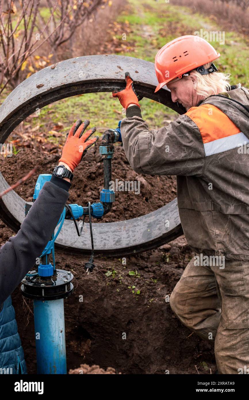 Workers install a water intake unit in a well. Installation of the ...