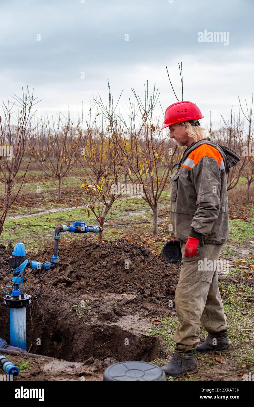 Workers install a water intake unit in a well. Installation of the ...