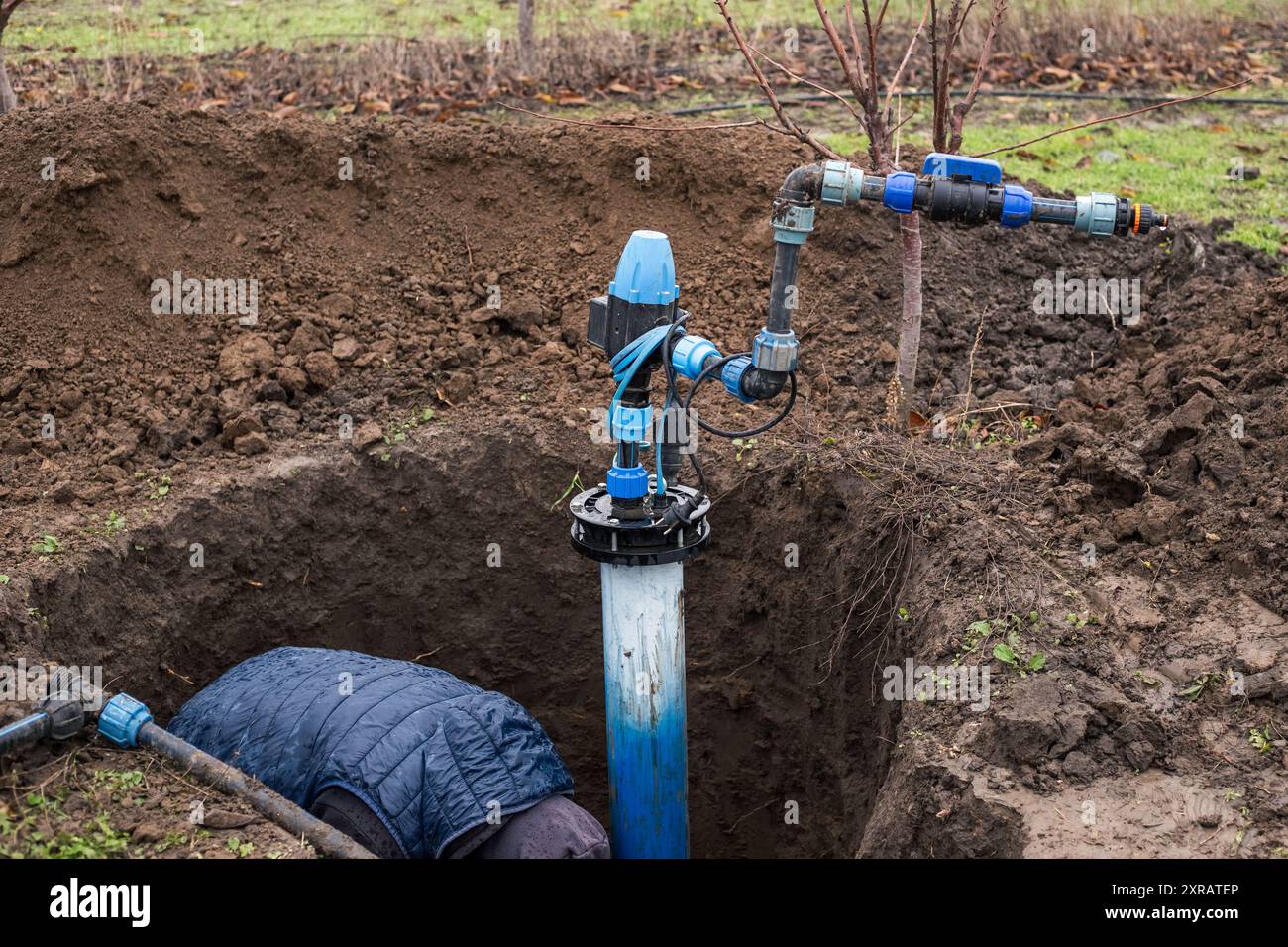 A worker installs a water intake unit in a well. Installation of the ...
