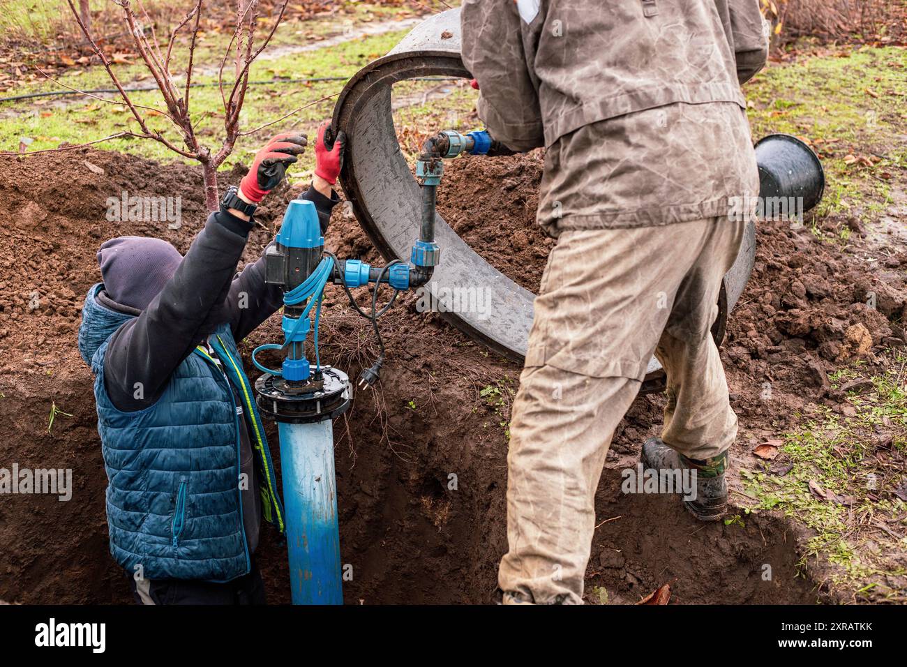 Workers install a water intake unit in a well. Installation of the ...