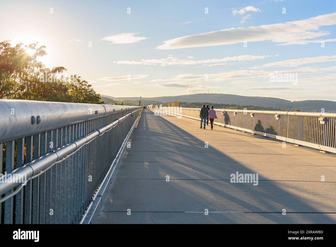 People walking along a pedestrian bridge at sunset in autumn Stock ...