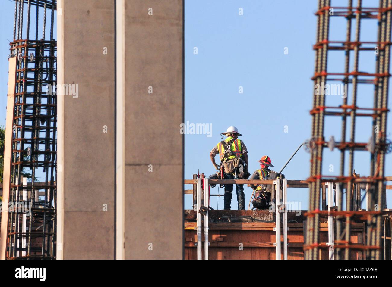 Two construction workers stand on top of a structure of a future ...