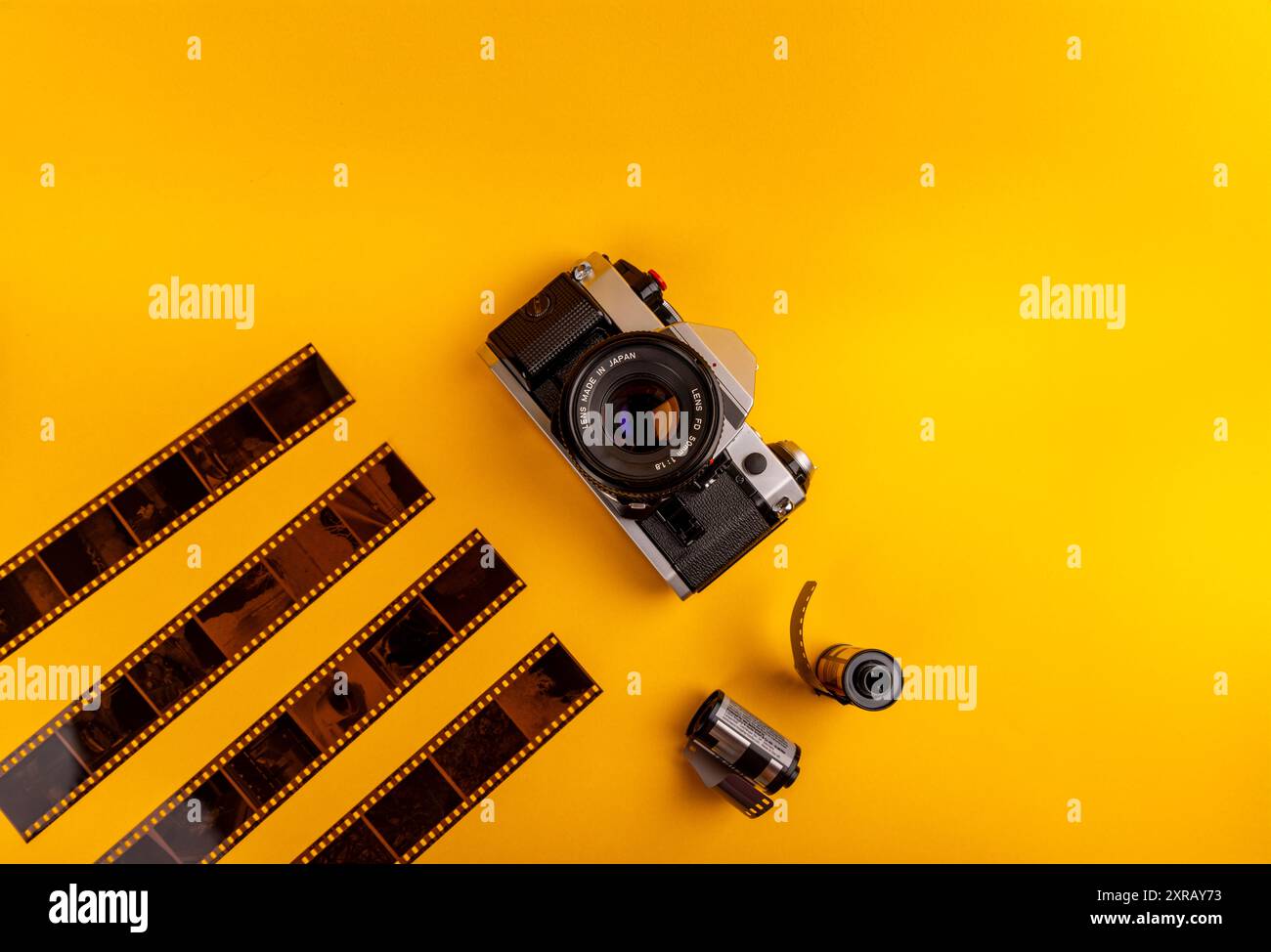 Top-down view of a vintage camera and used 35mm film rolls on a bright ...