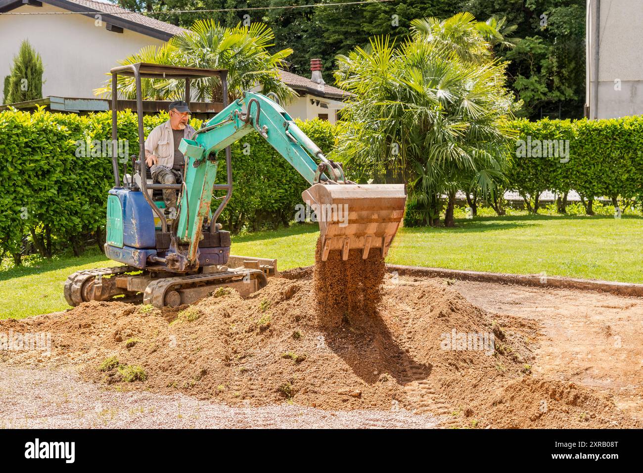 A worker on a mini excavator is digging the ground ahead of the house ...