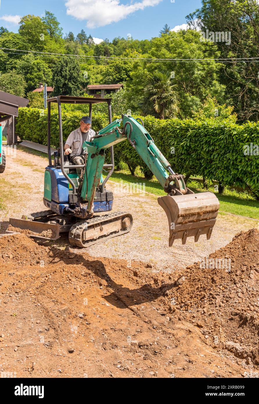 A worker on a mini excavator is digging the ground ahead of the house ...