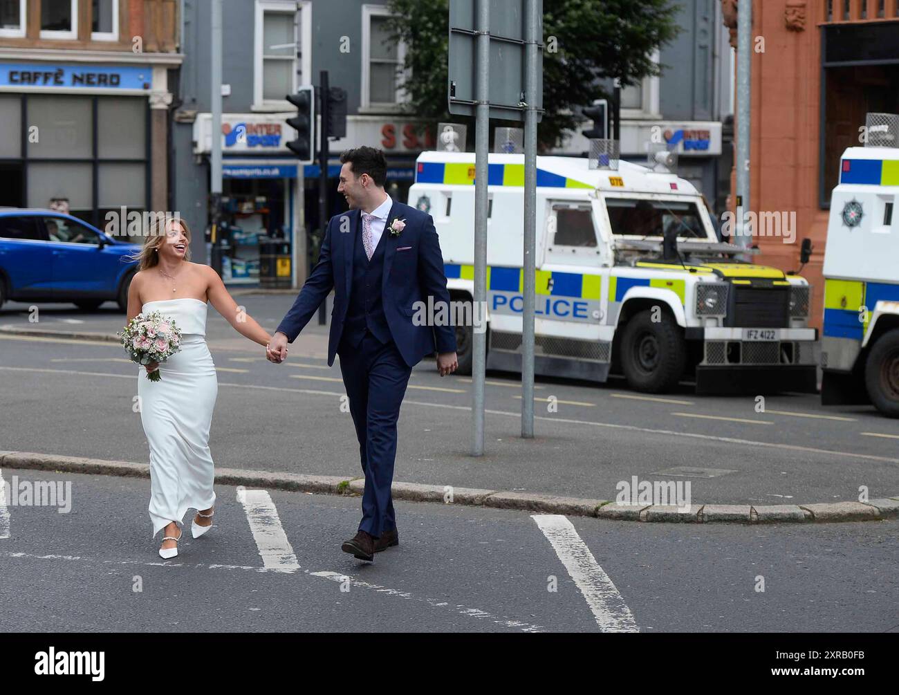 A newly married couple cross the road as PSNI officers line the streets ...