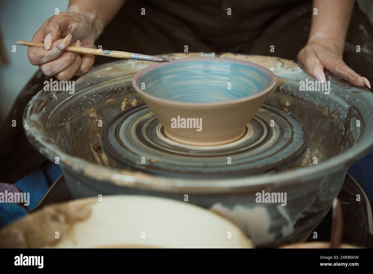Close up detail view at an artist making clay pottery on a spin wheel ...