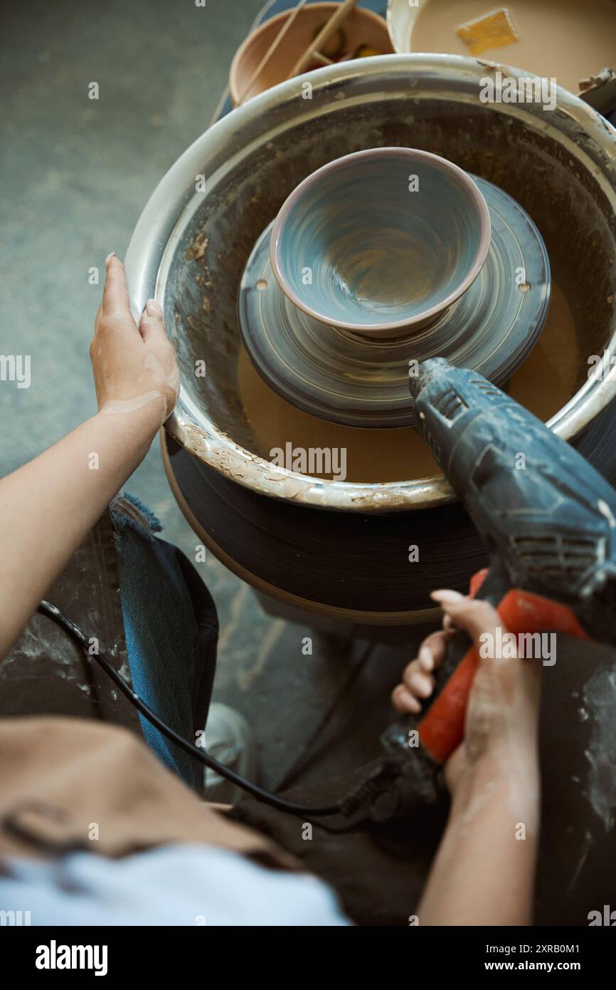 Top view of female drying earthenware bowl on pottery wheel using dryer ...
