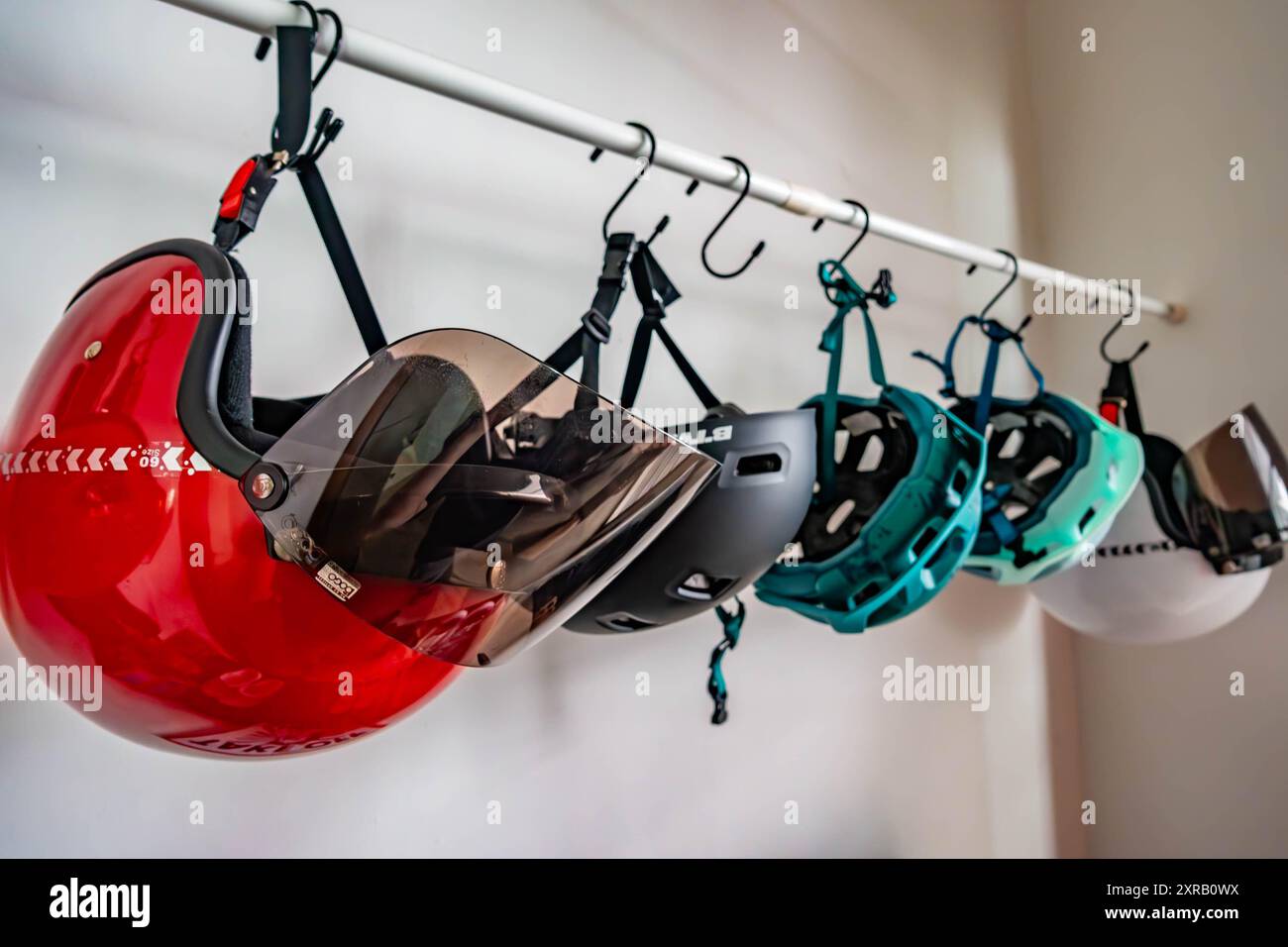 Crash helmets and bicycle helmets hanging on a rail in a hallway Stock ...
