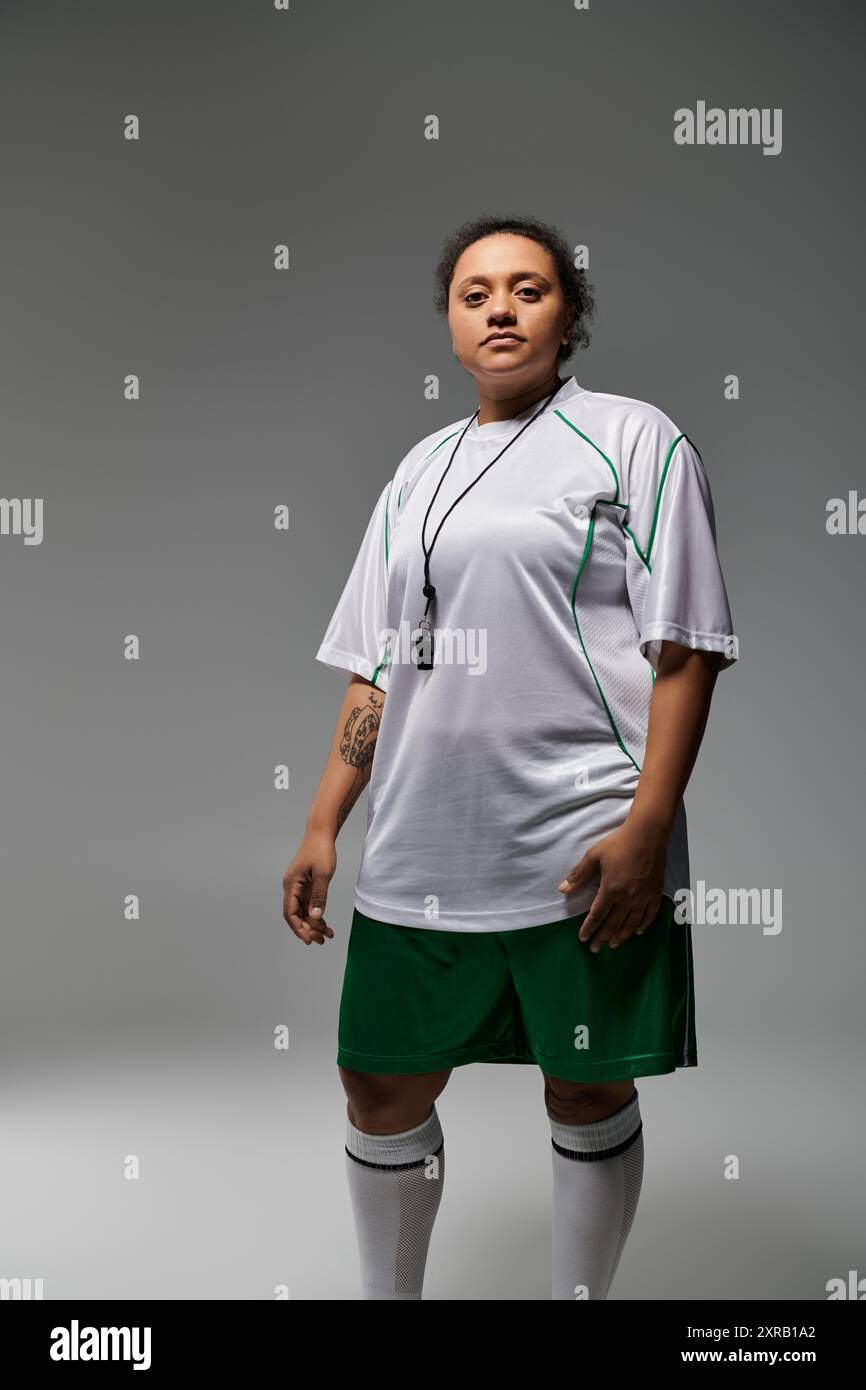 A female referee in uniform and with a whistle stands ready to ...