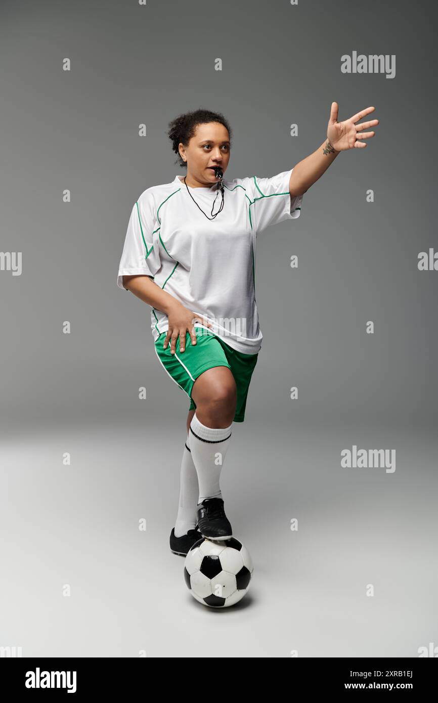 A female referee stands confidently with a whistle in hand, ready to ...