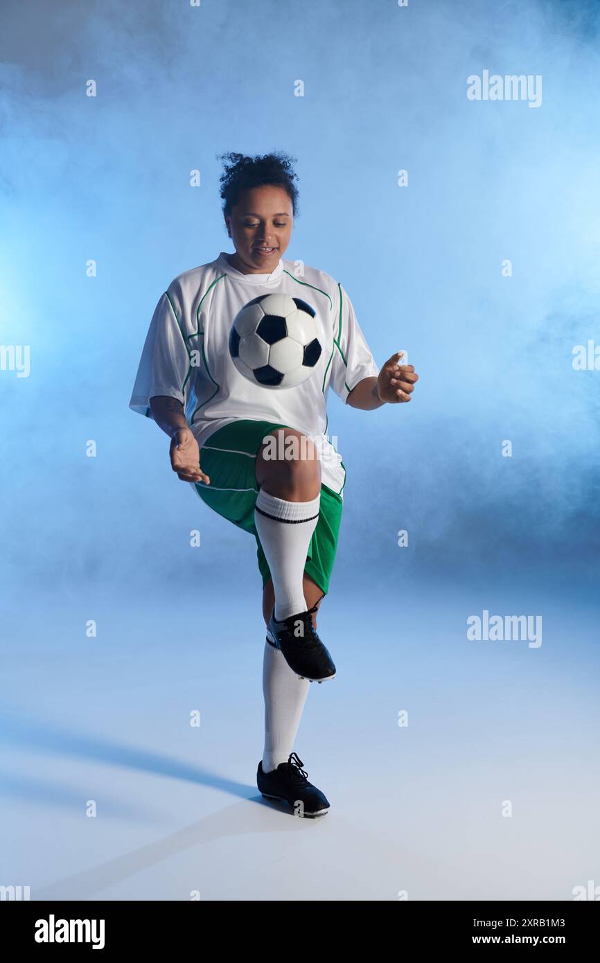 A female athlete practices juggling a soccer ball in a studio with blue ...