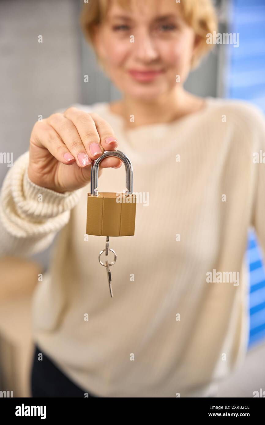Portrait of lady hold lock, working in storage unit Stock Photo - Alamy