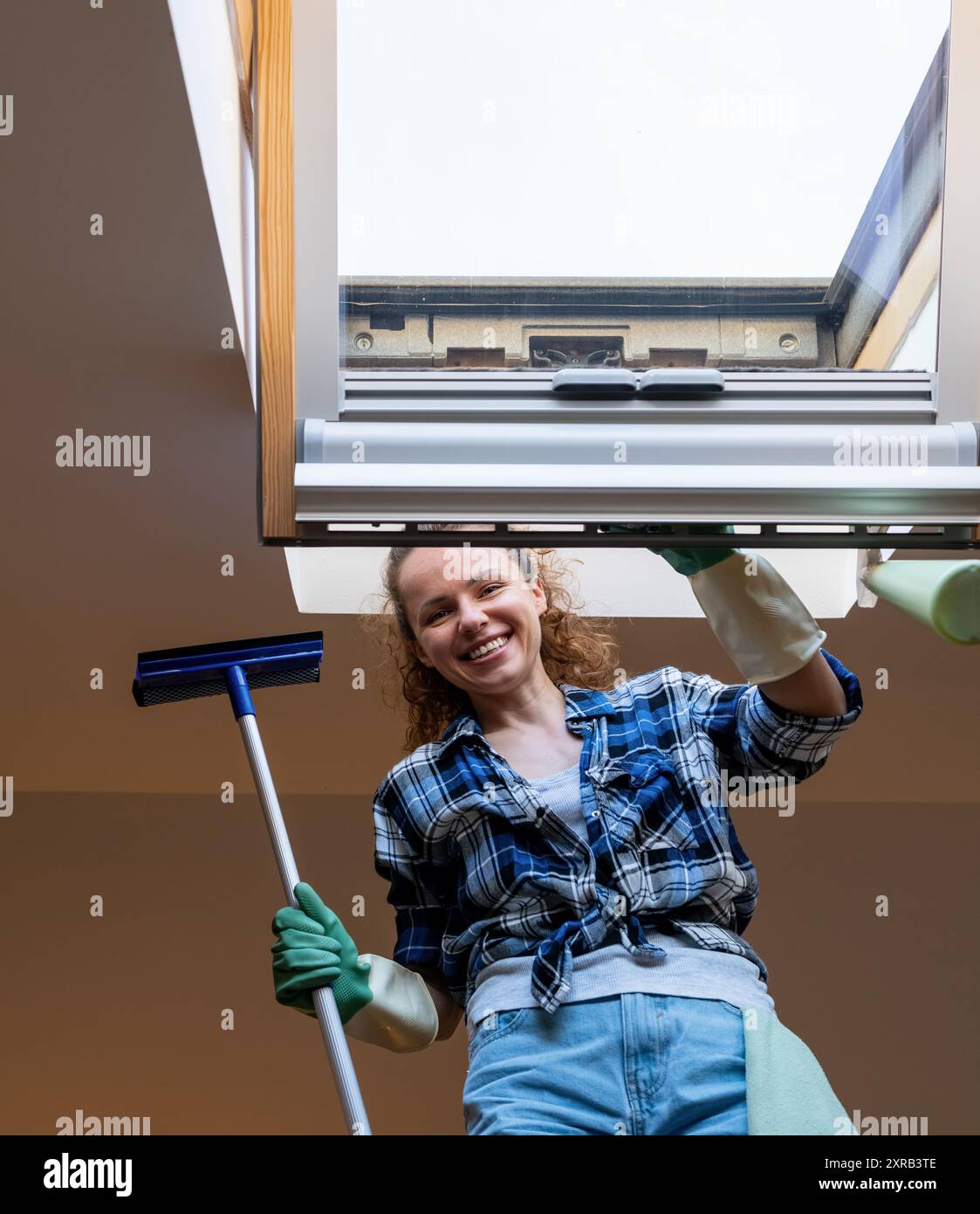 Happy young adult woman washing roof windows using squeegee Stock Photo ...
