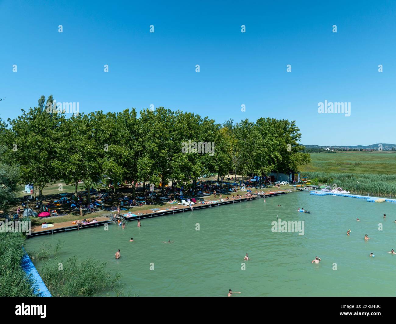 Beach in Lake Balaton. People bathing in the water of lake in hot ...