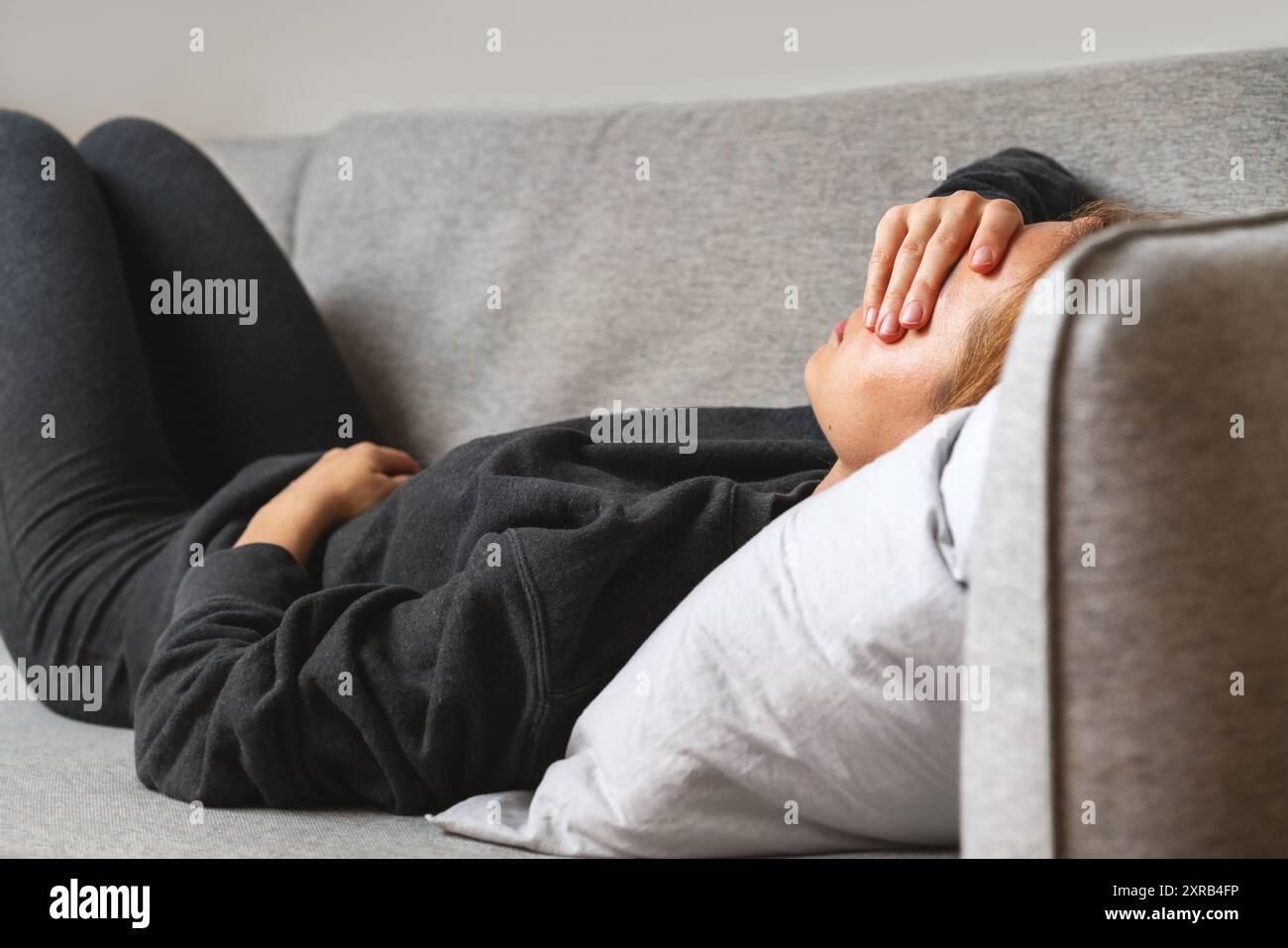 Feeling overwhelmed. Woman lying on back and covering face with hand ...