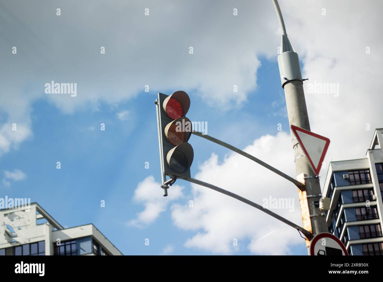A bright red traffic light is hanging down from a tall pole, clearly ...