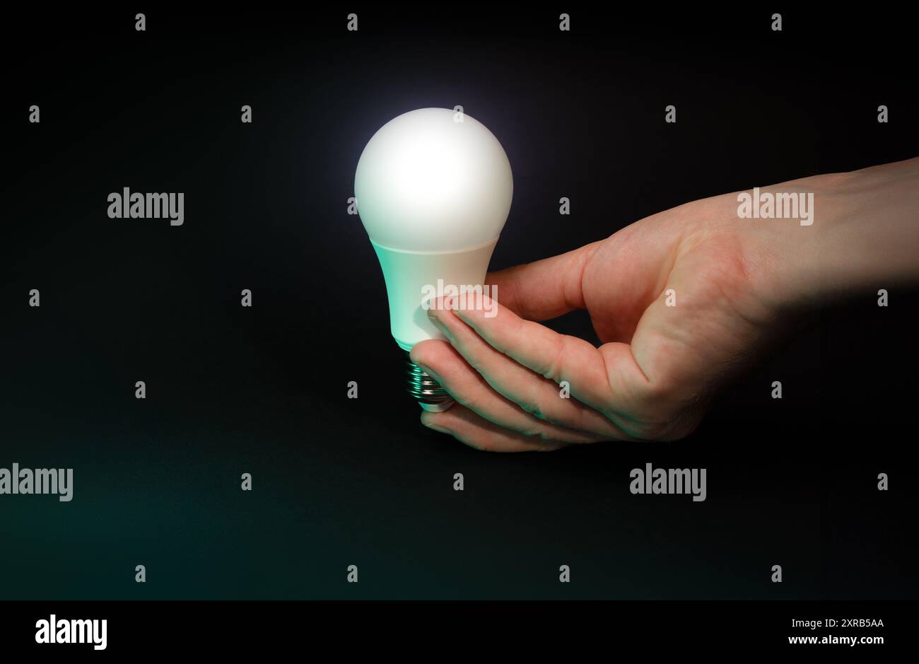 Hand holding glowing light bulb. Clean dark background. Ideas and ...
